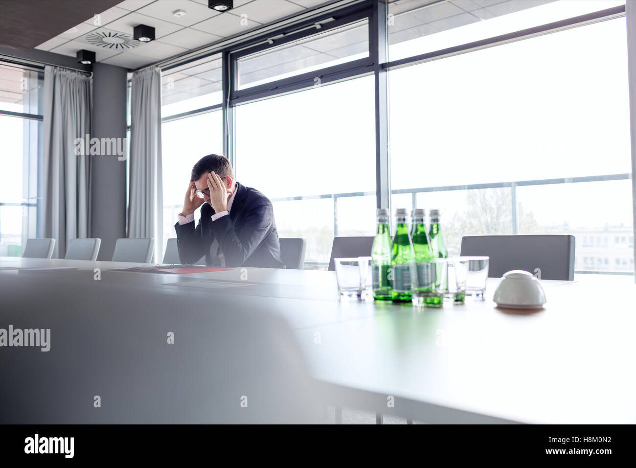 Mature businessman suffering from headache at conference table Stock ...