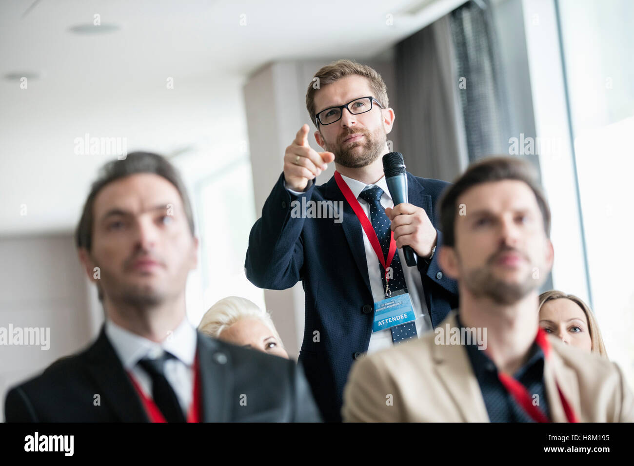 Businessman gesturing while asking question during seminar Stock Photo ...