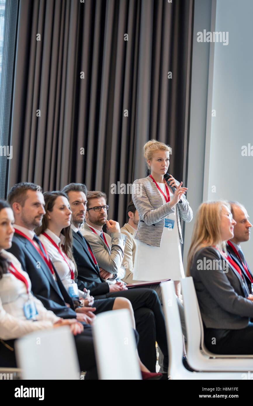 Businesswoman asking questions during seminar in convention center ...