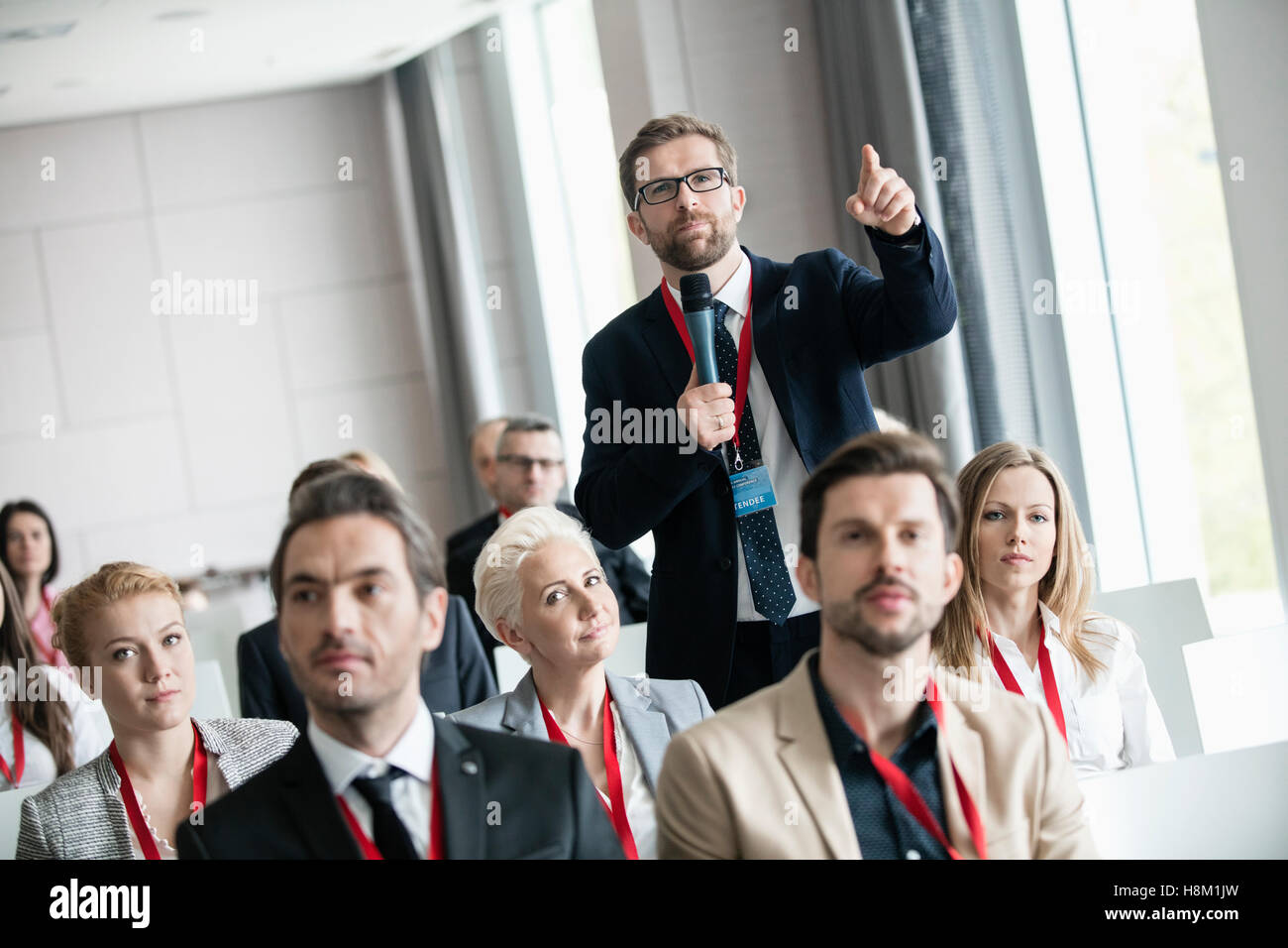 Businessman gesturing while asking question during seminar in ...