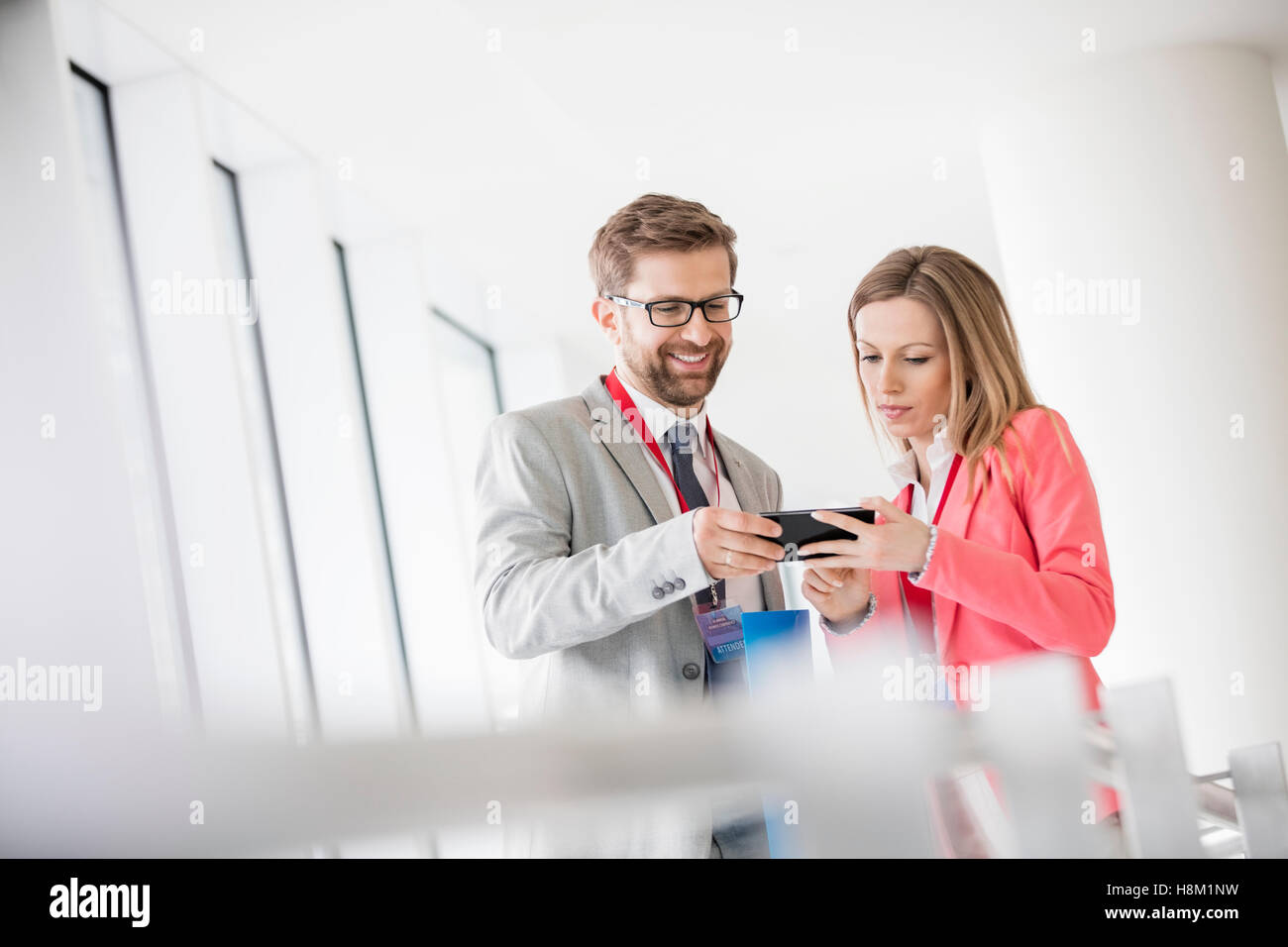 Business people using smart phone in convention center Stock Photo - Alamy