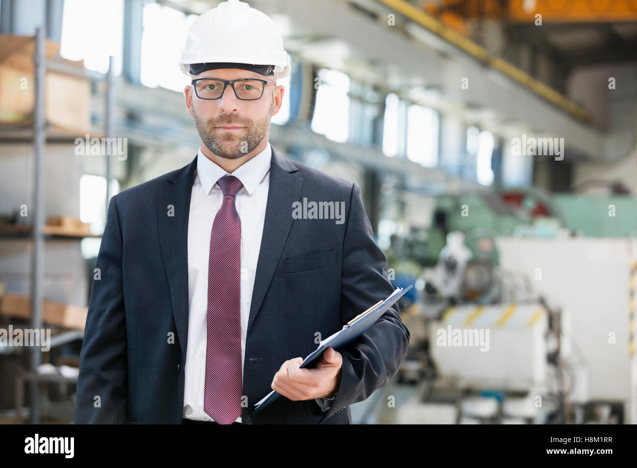 Portrait of confident mid adult male supervisor holding clipboard in ...