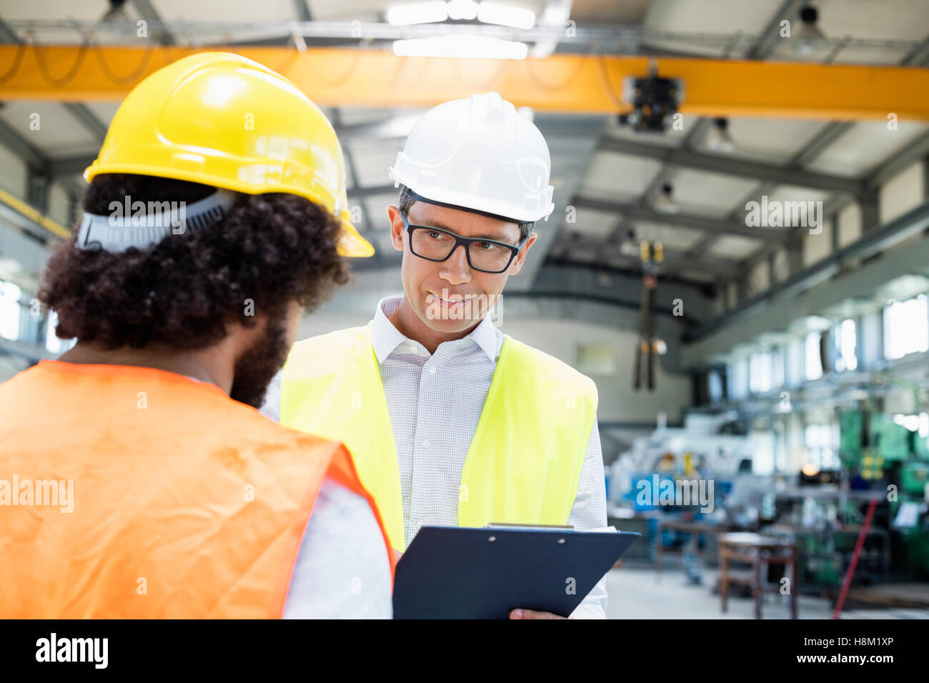Male supervisor discussing with manual worker in metal industry Stock ...