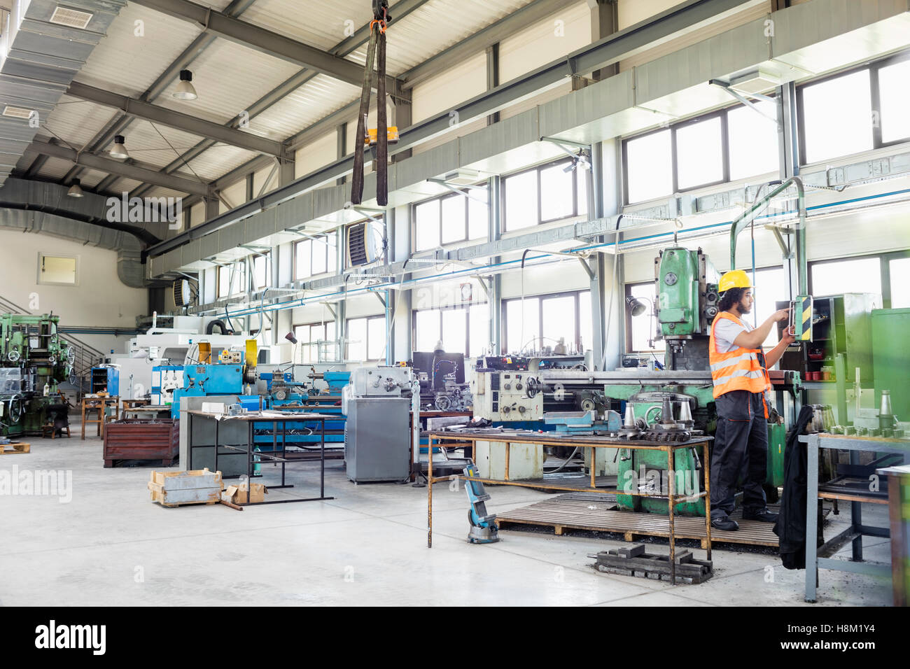 Young manual worker operating machinery in metal industry Stock Photo ...