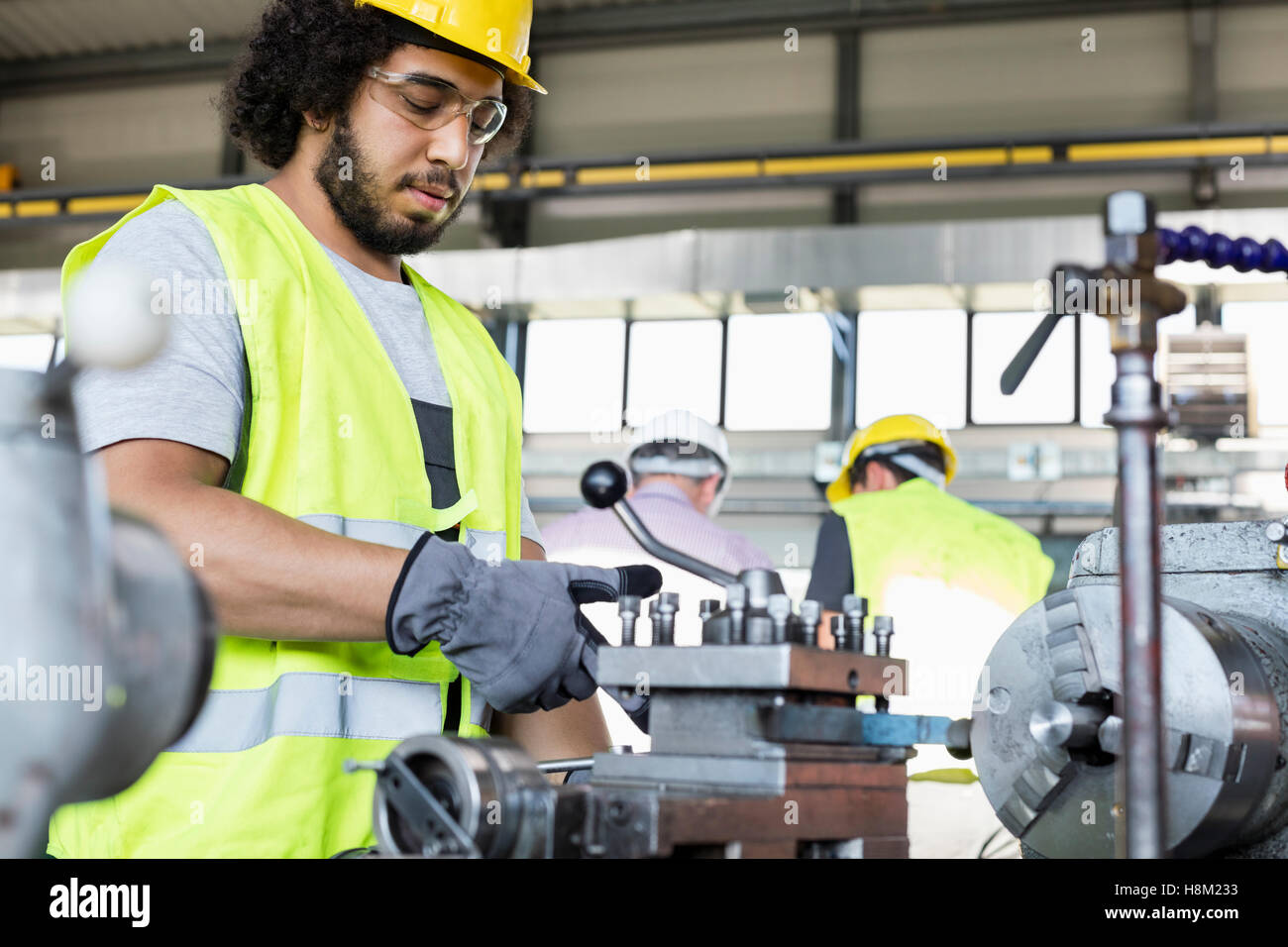 Young manual worker operating machinery in metal industry Stock Photo ...