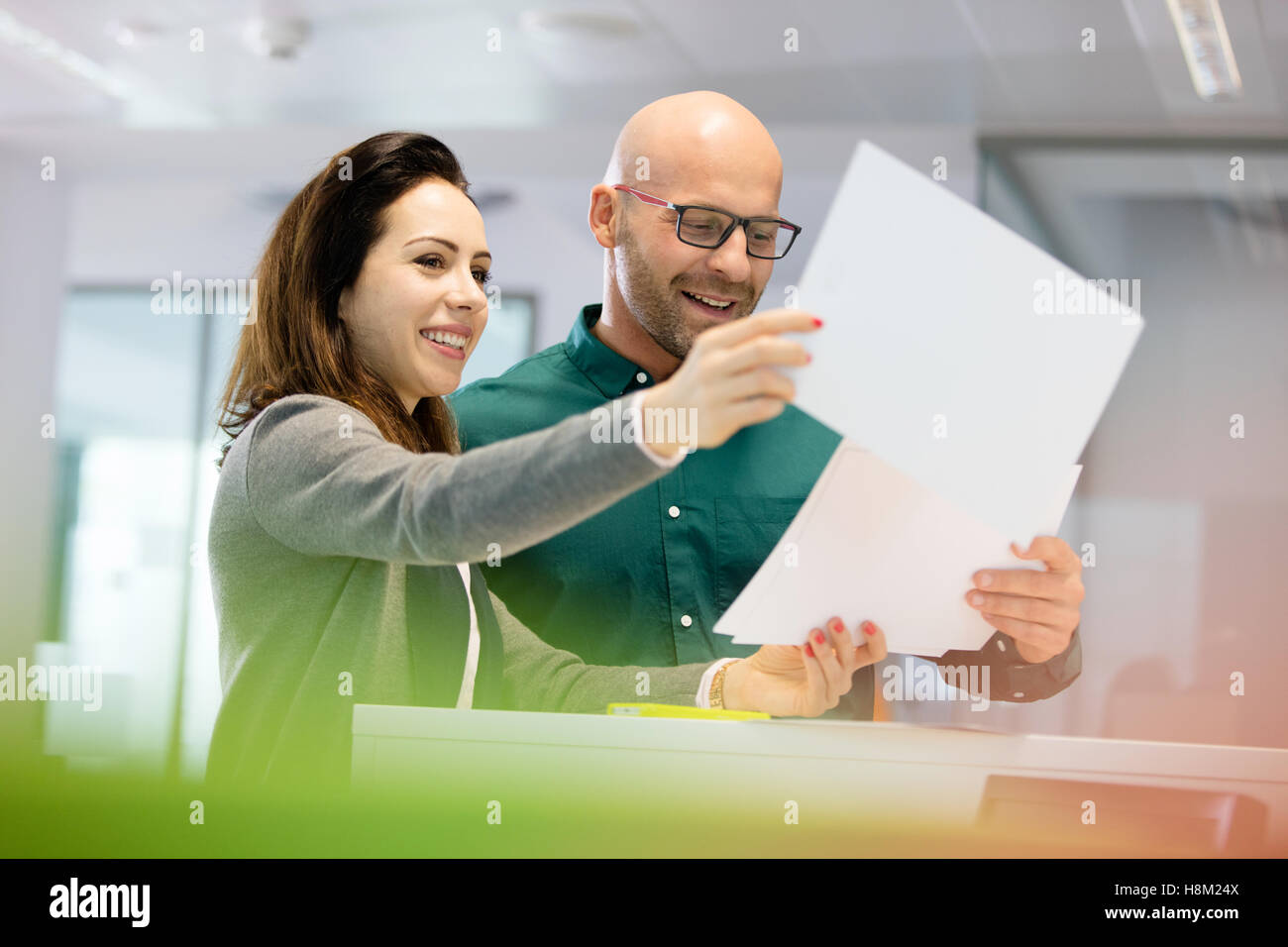 Smiling business people discussing over paperwork in office Stock Photo ...