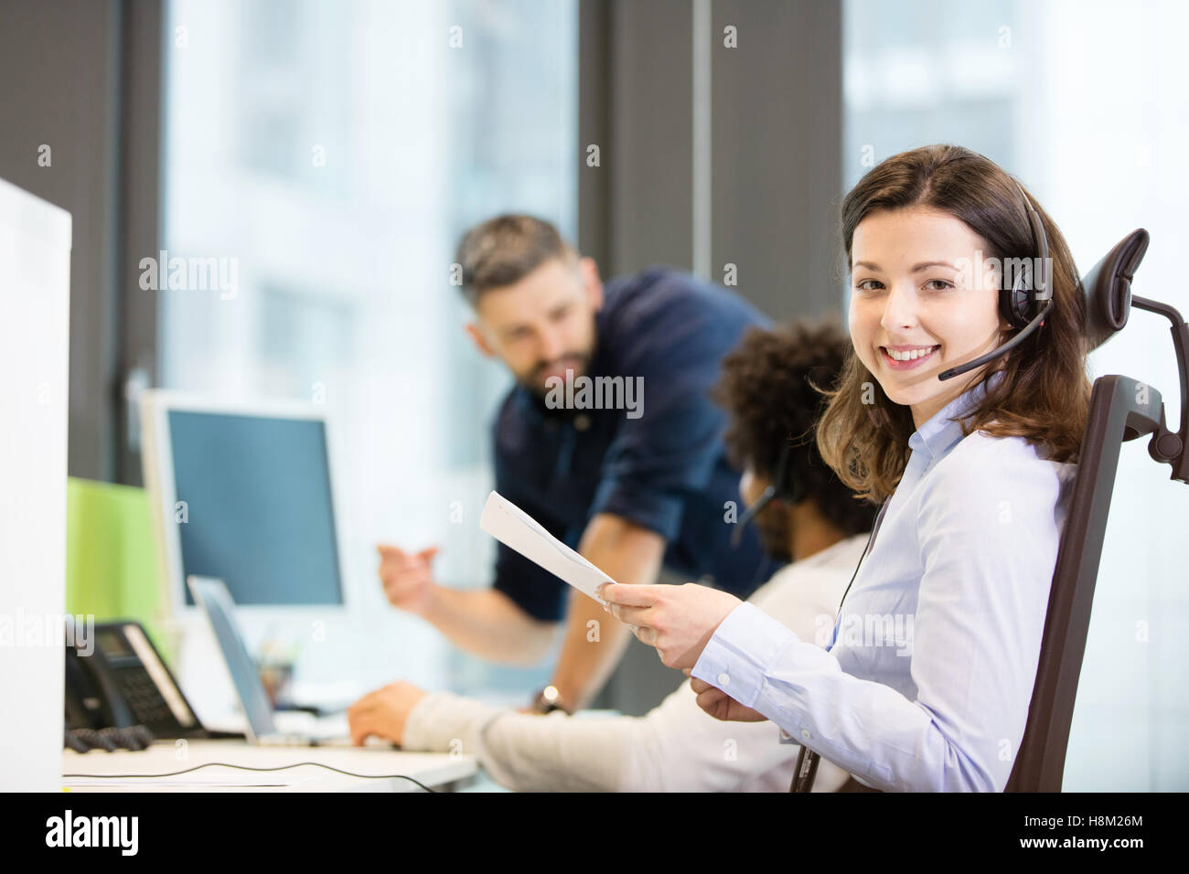 Portrait of smiling customer service representative holding documents ...