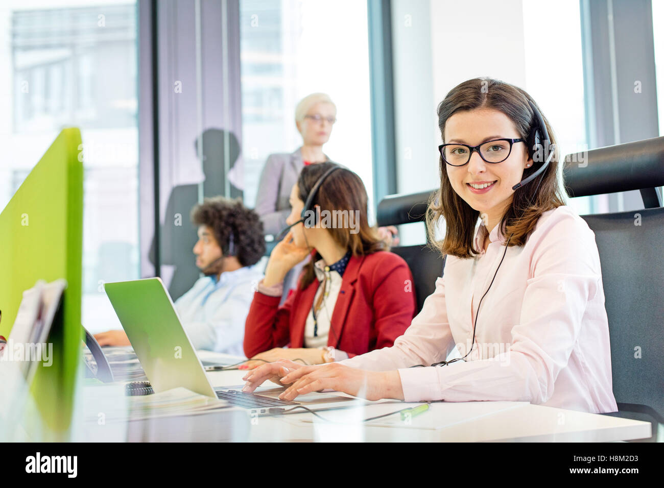 Portrait of smiling customer service representative using laptop while ...