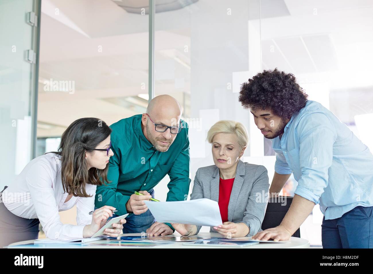 Multi-ethnic business people discussing over document at table in ...