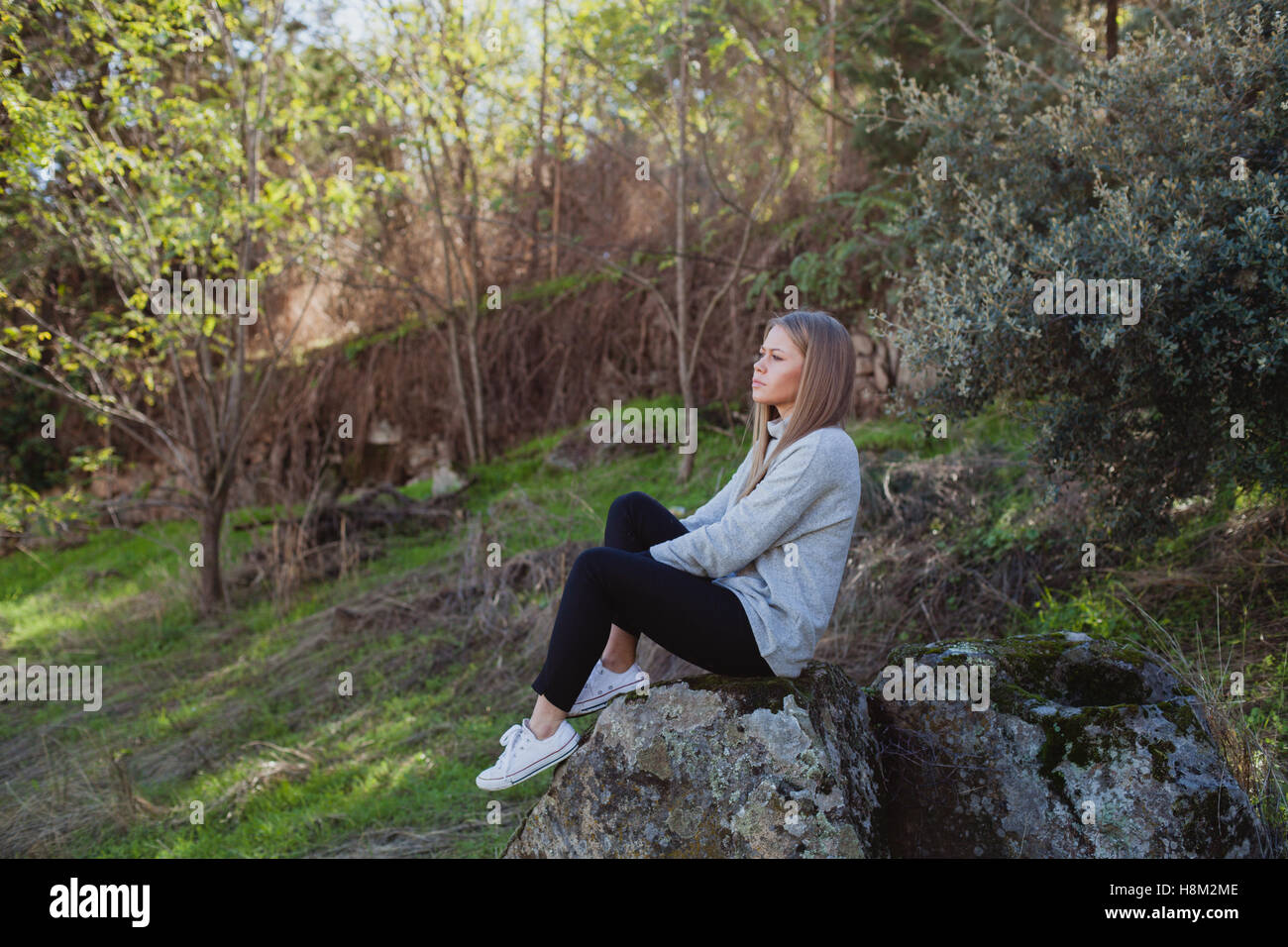 Young woman sitting on a big stone in a relaxed day Stock Photo - Alamy