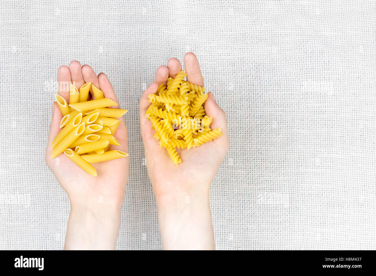 Handful of uncooked pasta flat lay. Female hands holding heap of raw ...