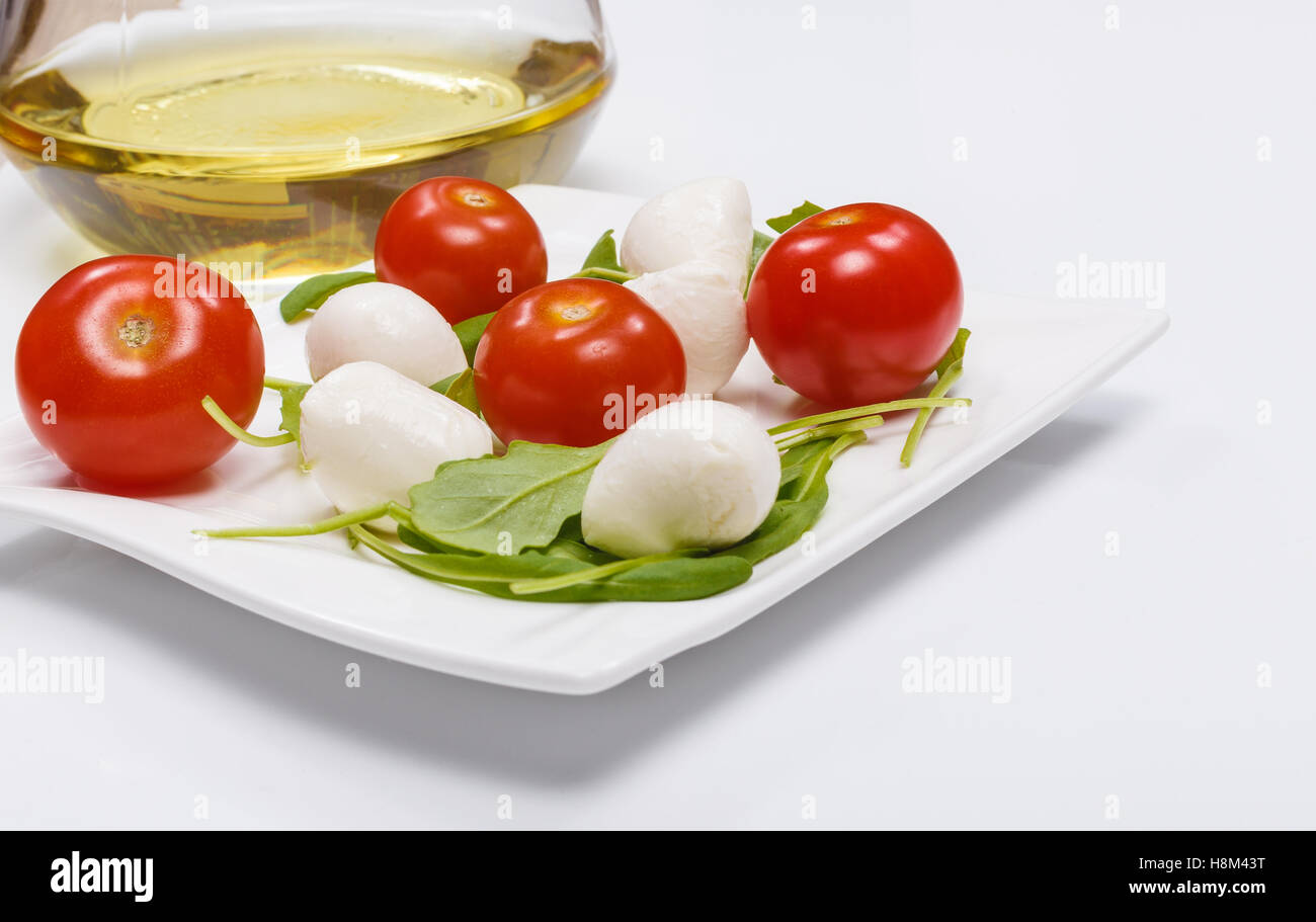 Vegetarian raw food plate with tomato, ruccola and mozzarella next to a ...