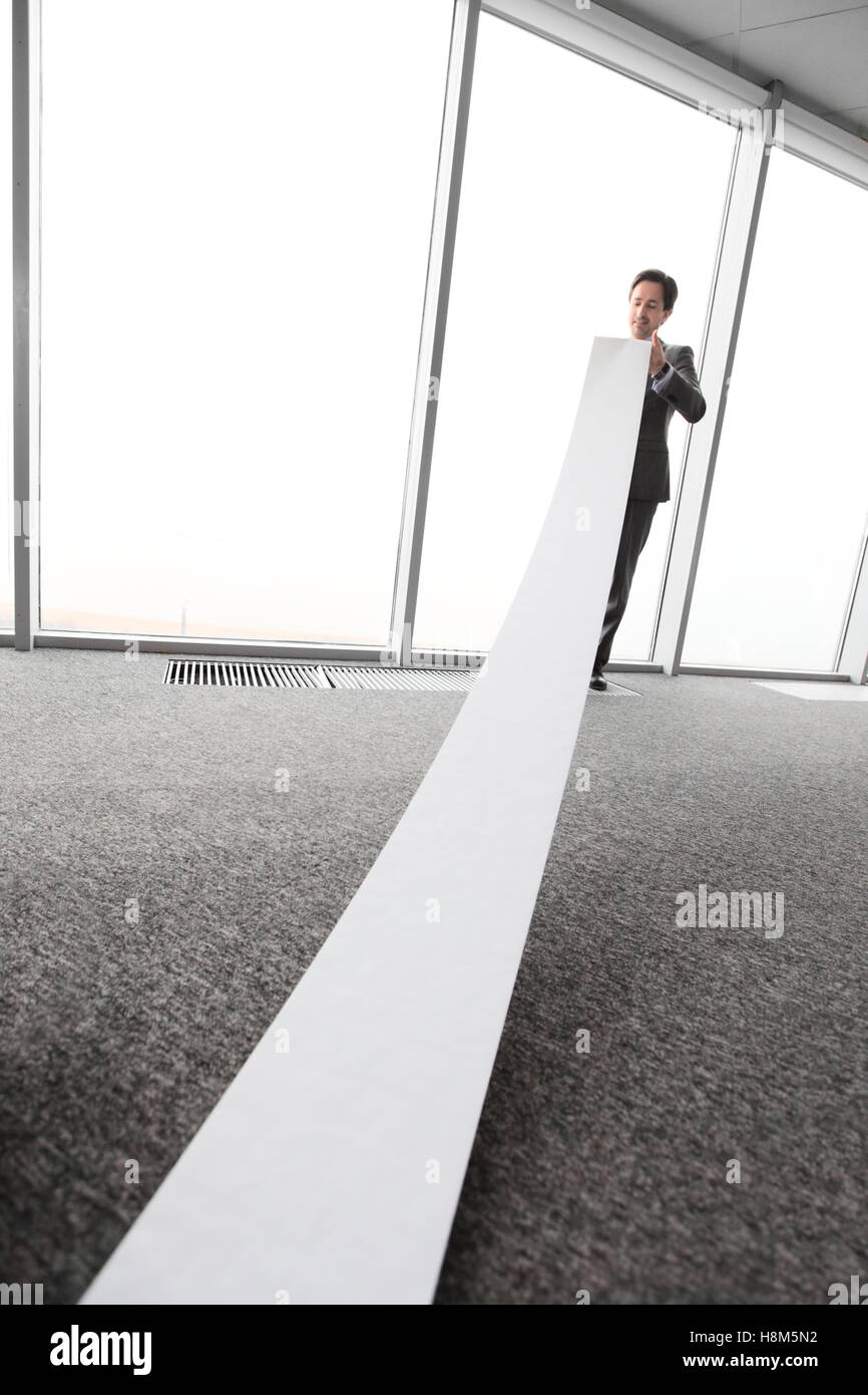 Office worker unrolling long sheet of paper Stock Photo - Alamy