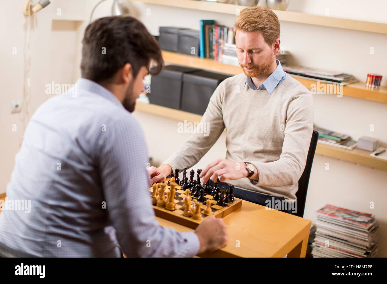 Two young men playing chess in room Stock Photo - Alamy