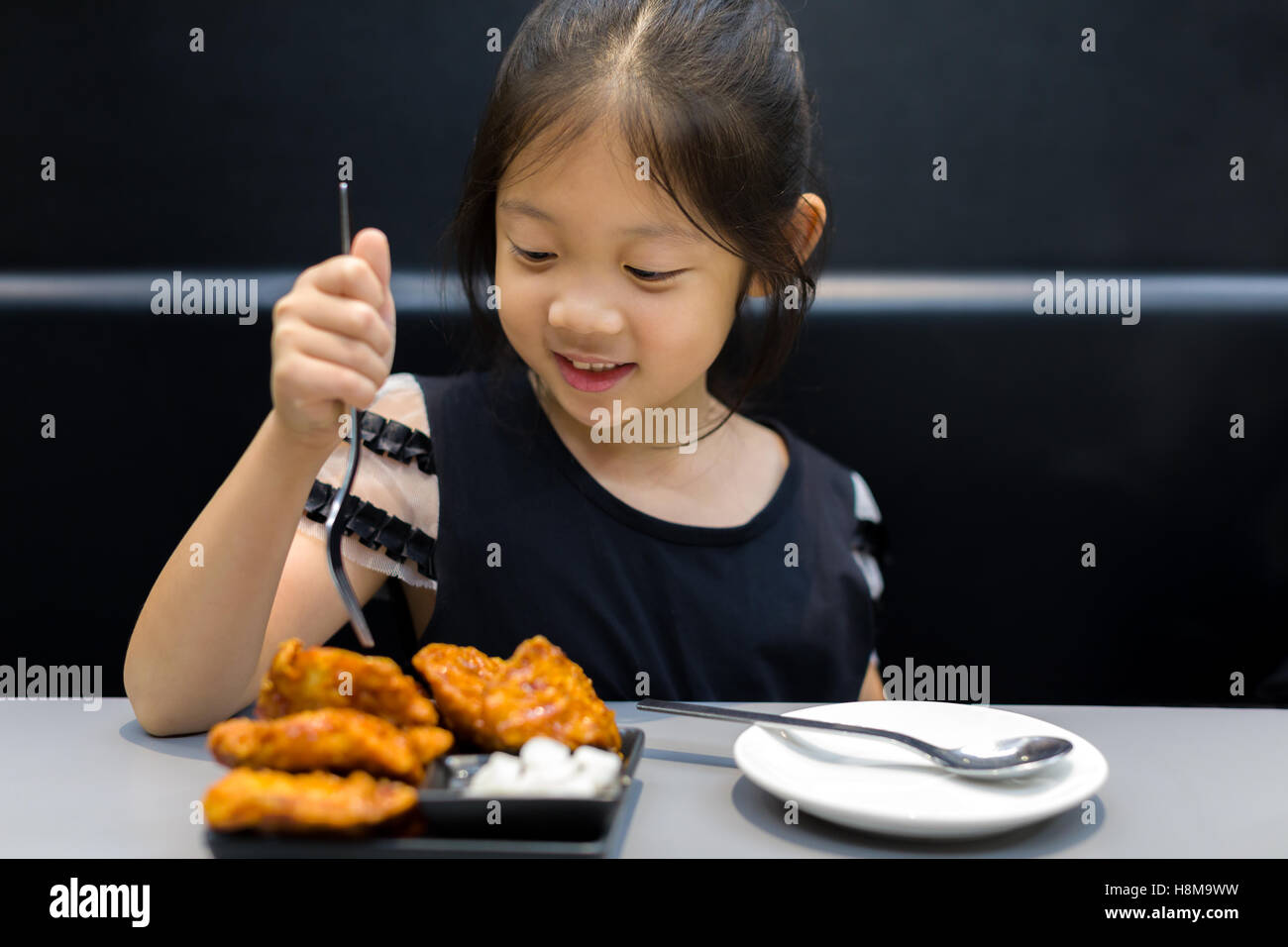 Hungry Asian child eating fried chicken at restaurant Stock Photo - Alamy