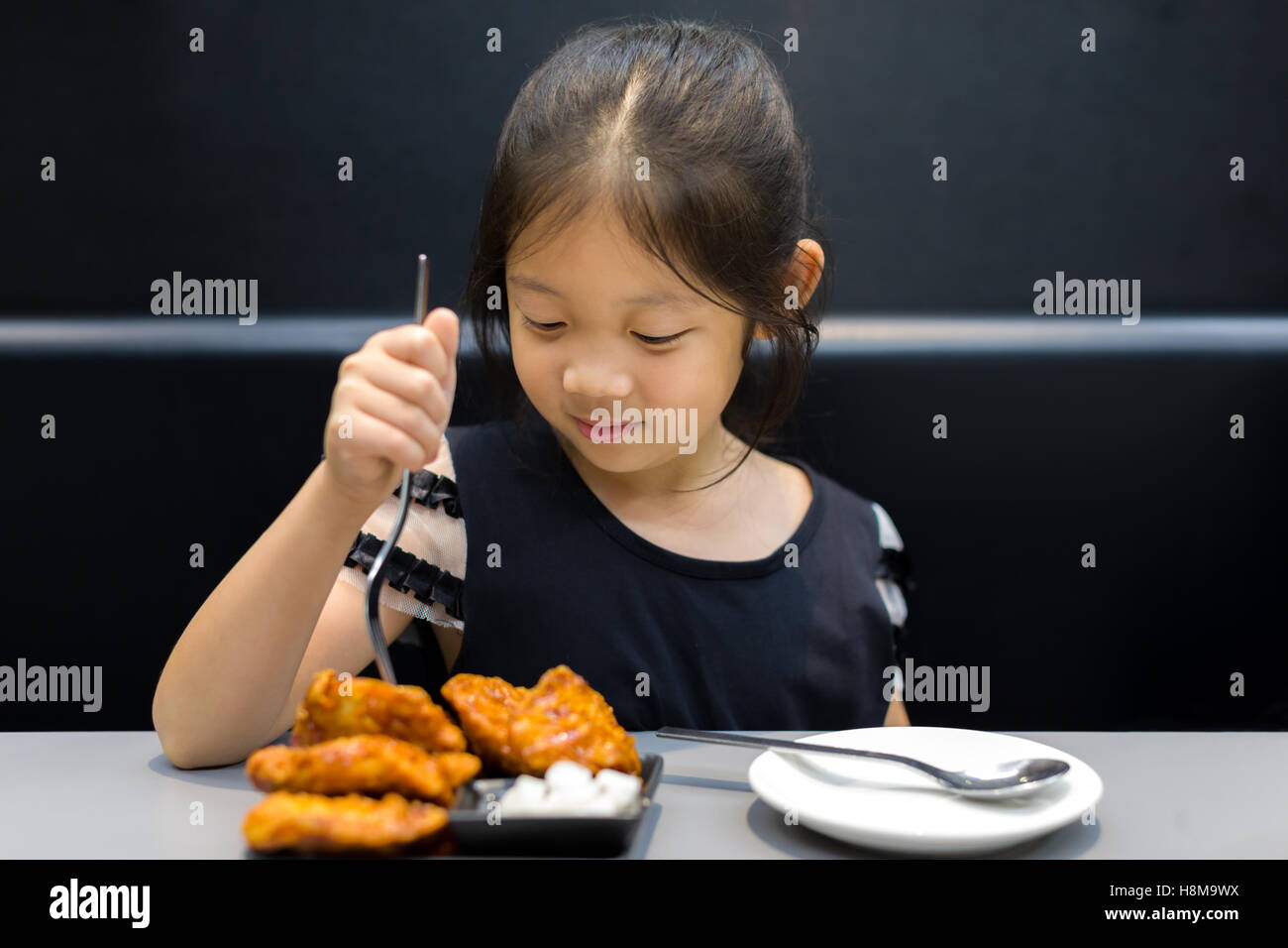 Hungry Asian kid eating fried chicken at restaurant Stock Photo - Alamy