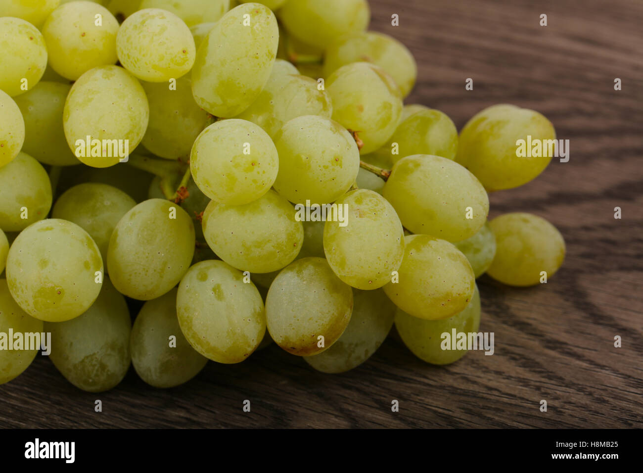 Sweet yellow grape heap on the wood background Stock Photo - Alamy