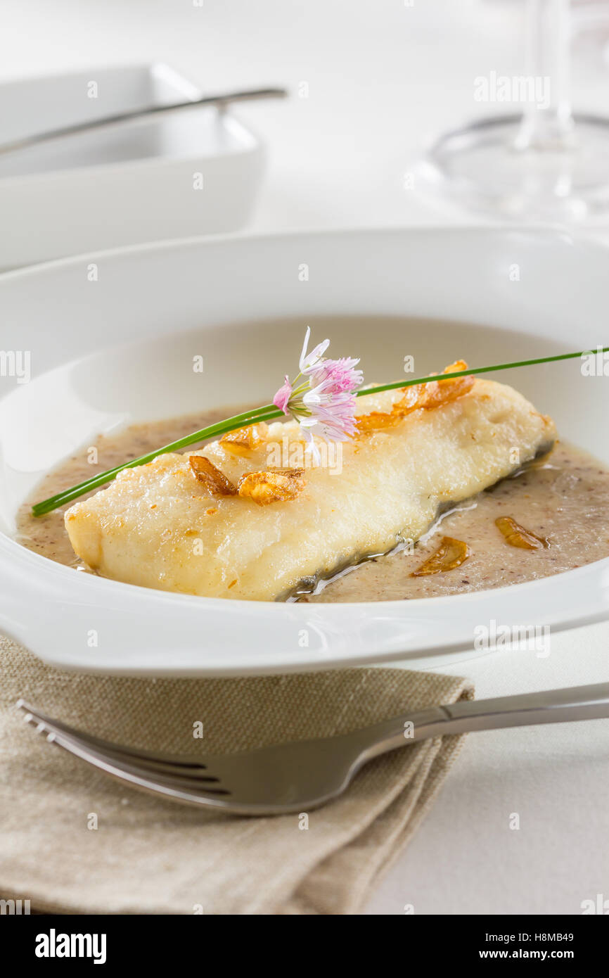 A fried hake fillet served a garlic sauce and garnished with fried ...