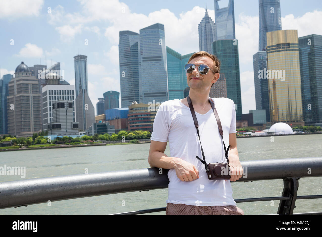 Thoughtful man leaning on railing against Shanghai World Financial ...