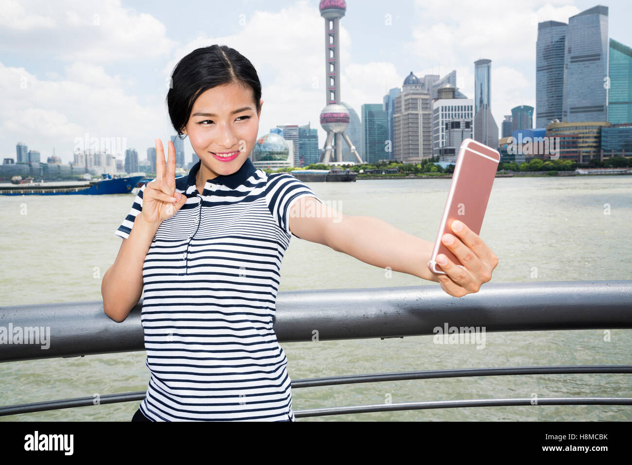 Beautiful woman gesturing peace sign while taking selfie through smart ...