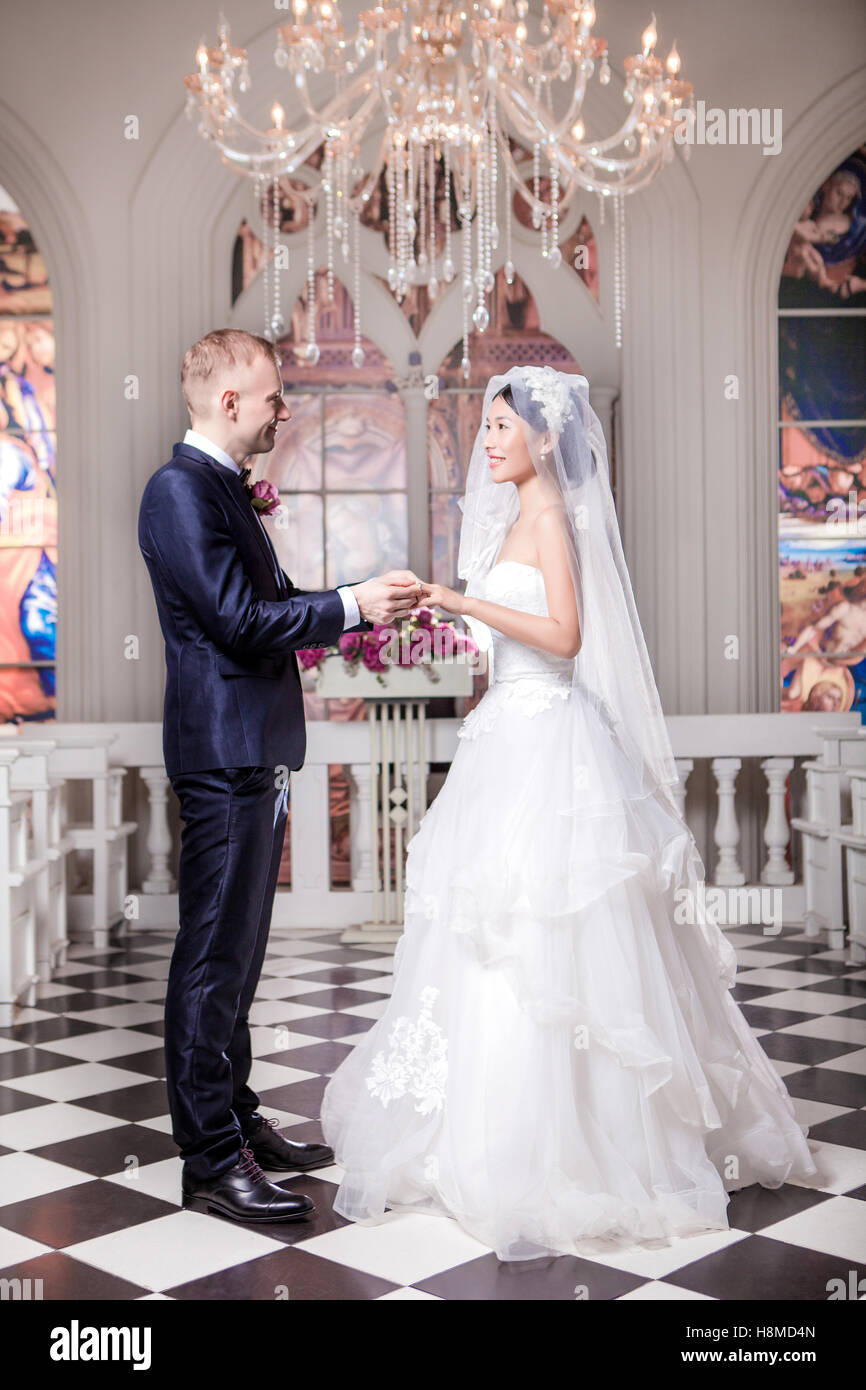 Full length side view of wedding couple exchanging rings in church ...