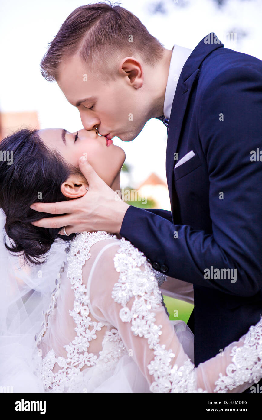 Side view of romantic wedding couple kissing against sky Stock Photo ...