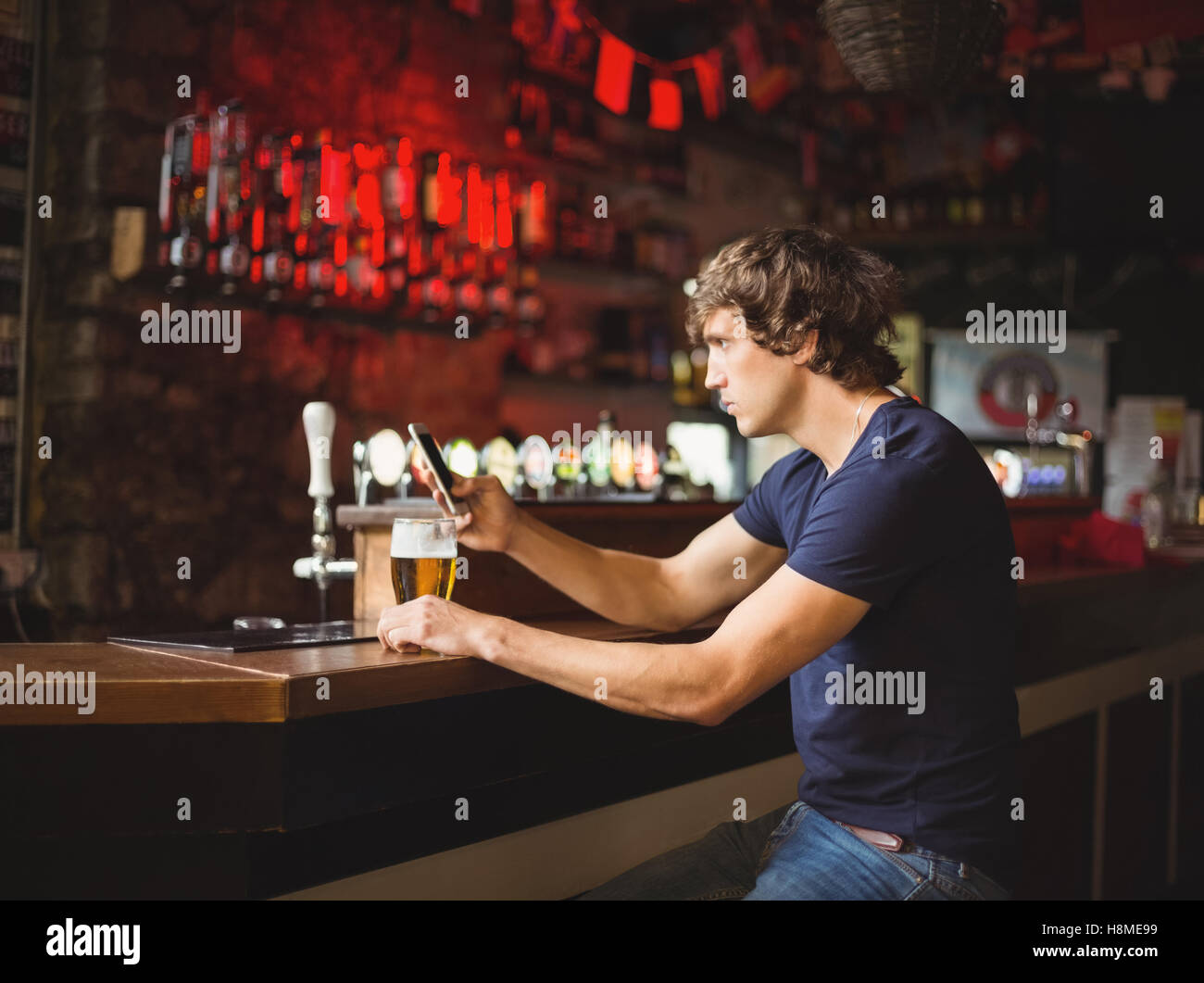Man with glass of beer using mobile phone in counter Stock Photo - Alamy