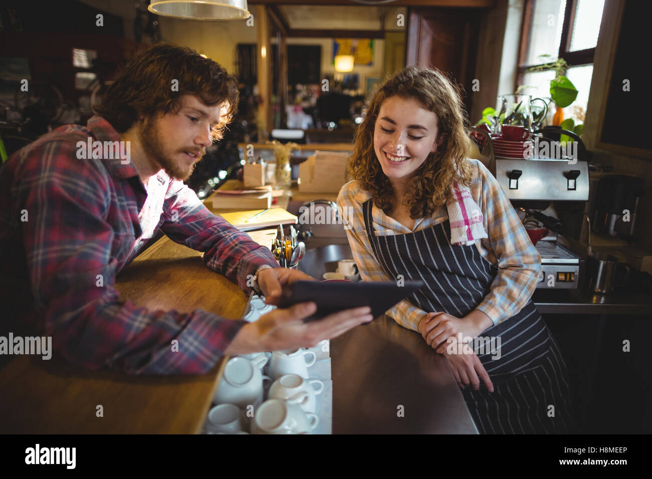 Customer showing digital tablet to waitress Stock Photo - Alamy