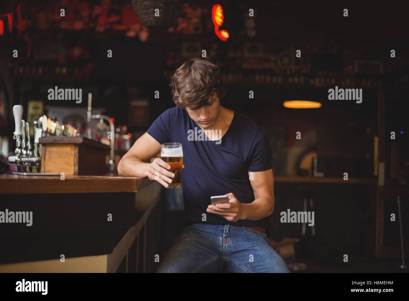 Man using mobile phone while having glass of beer Stock Photo - Alamy