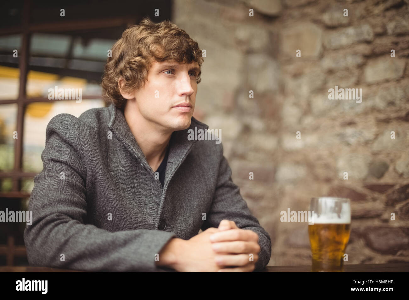 Man sitting in bar with glass of beer on table Stock Photo - Alamy
