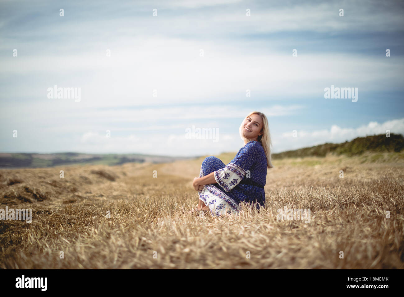 Blonde woman sitting in field Stock Photo - Alamy