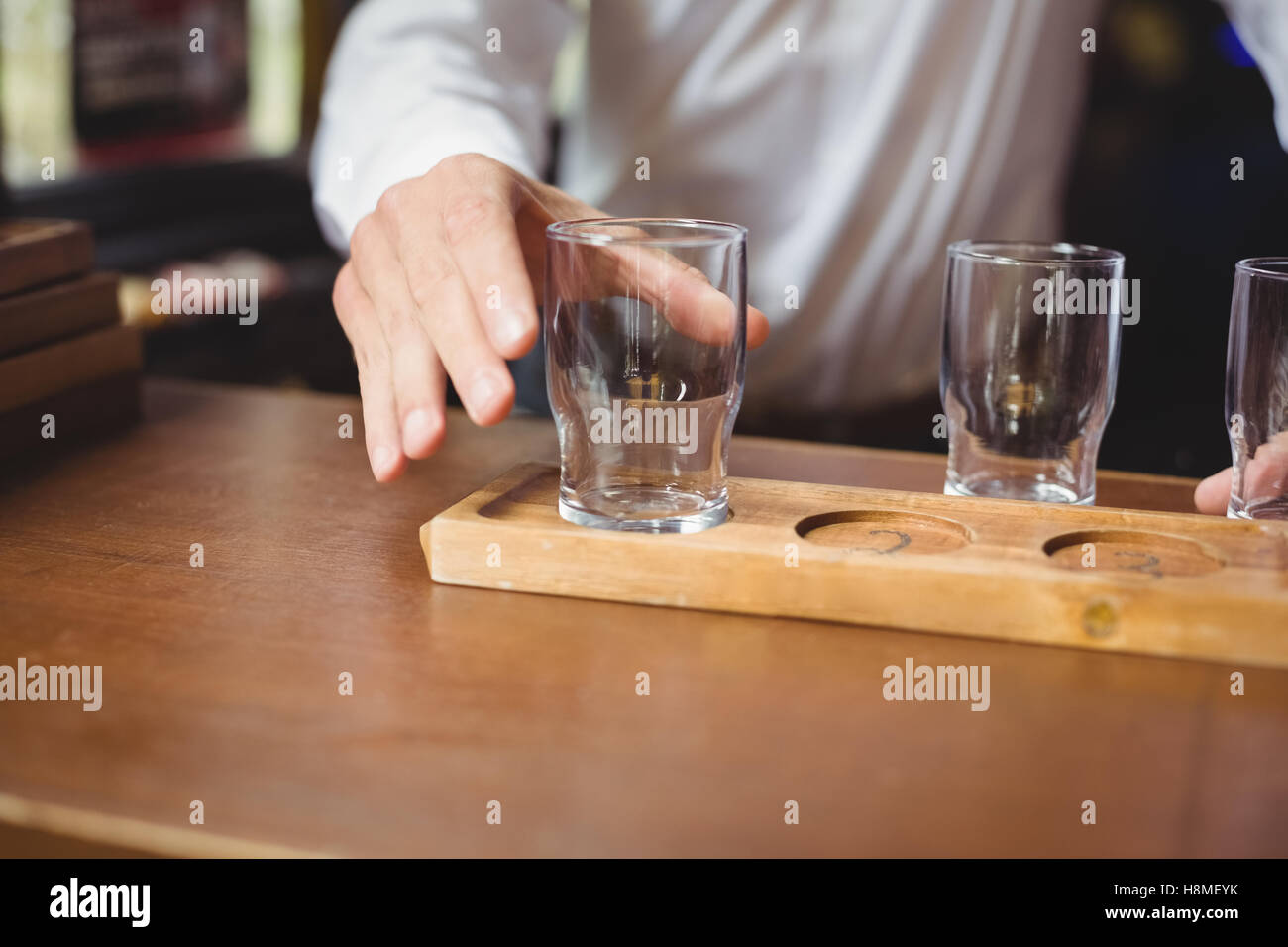 Bartender arranging beer glass on tray at bar counter Stock Photo - Alamy
