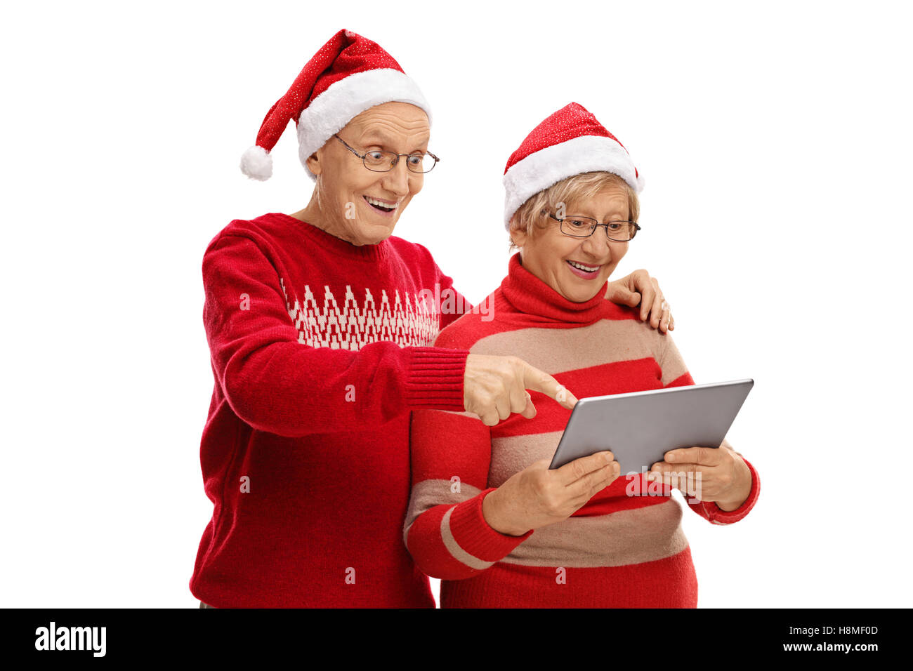 Seniors with Santa hats looking at a tablet isolated on white ...
