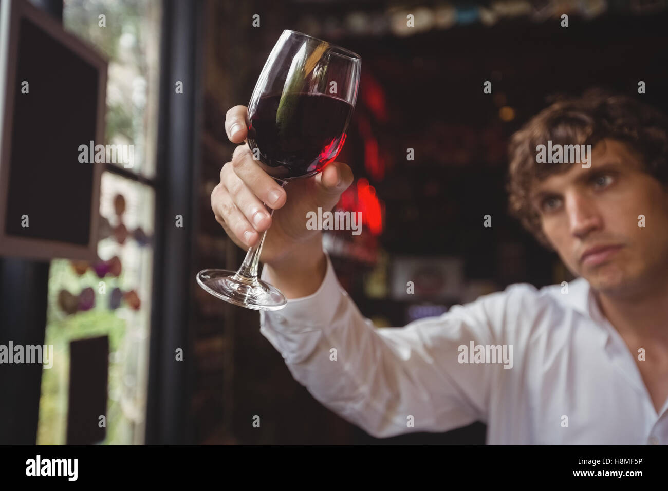 Bartender looking at glass of red wine Stock Photo - Alamy