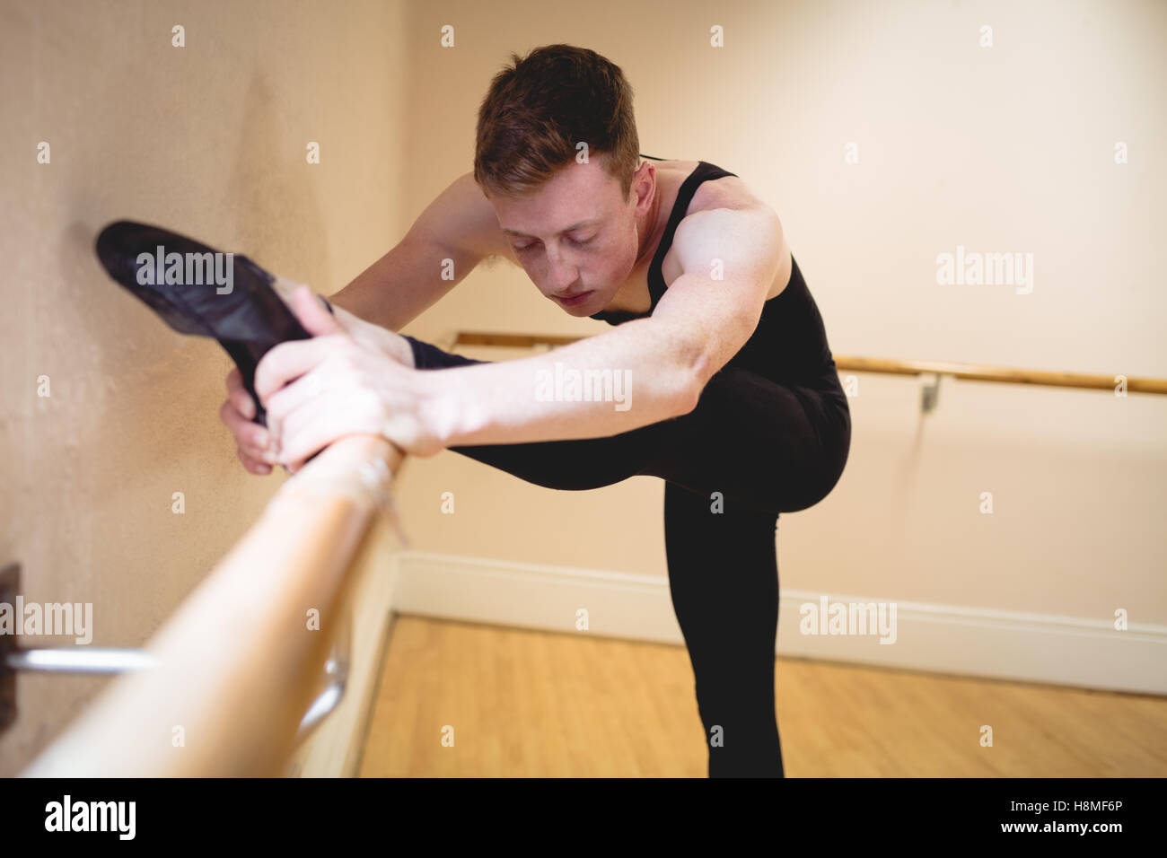 Ballerino stretching on a barre while practising ballet dance Stock ...