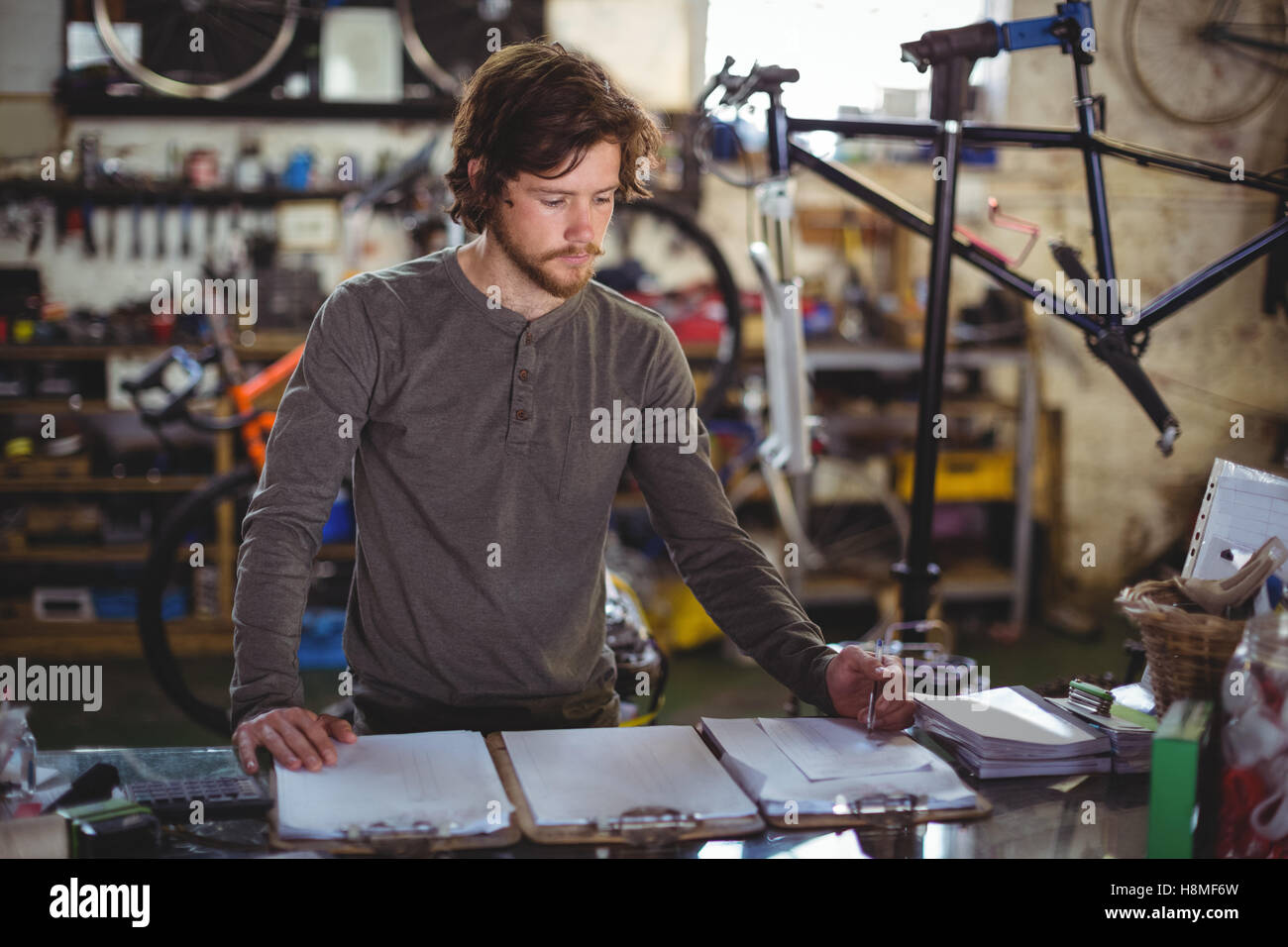 Mechanic writing on clipboard at counter Stock Photo - Alamy