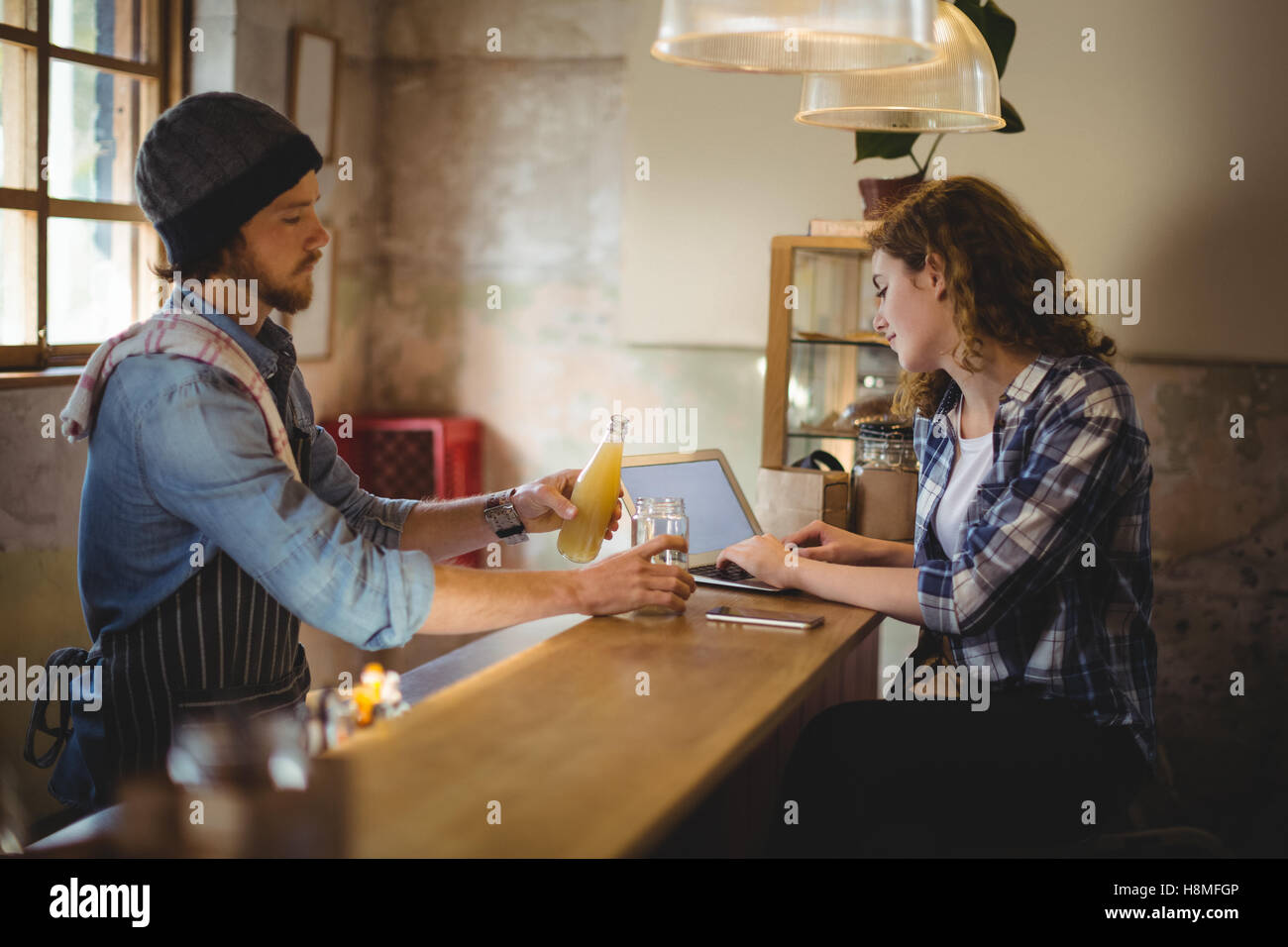 Waiter serving juice to mechanic at counter Stock Photo - Alamy