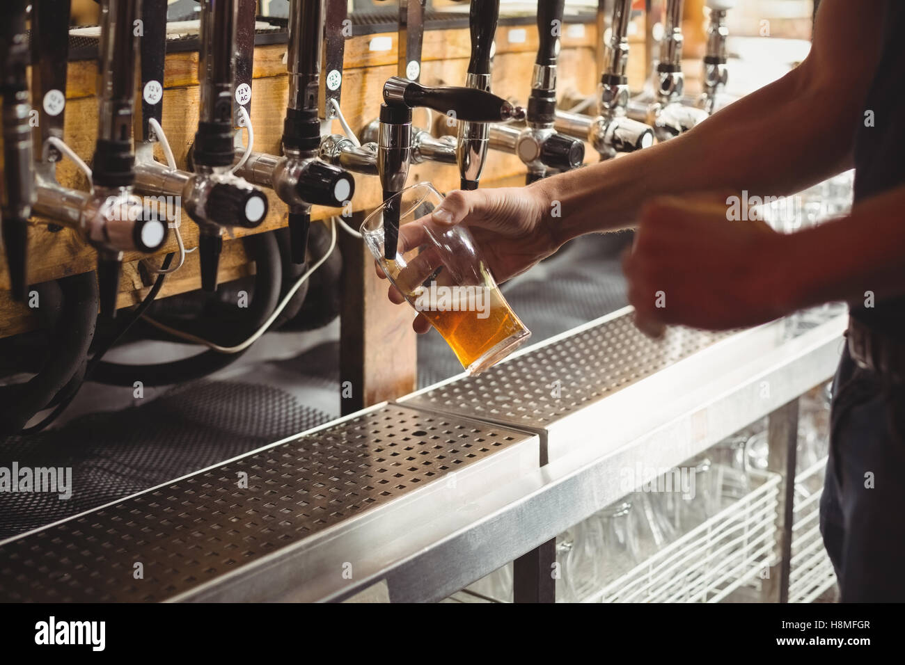 Mid section of bar tender filling beer from bar pump Stock Photo - Alamy