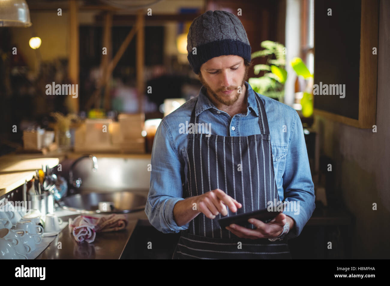 Handsome waiter using digital tablet at counter Stock Photo - Alamy