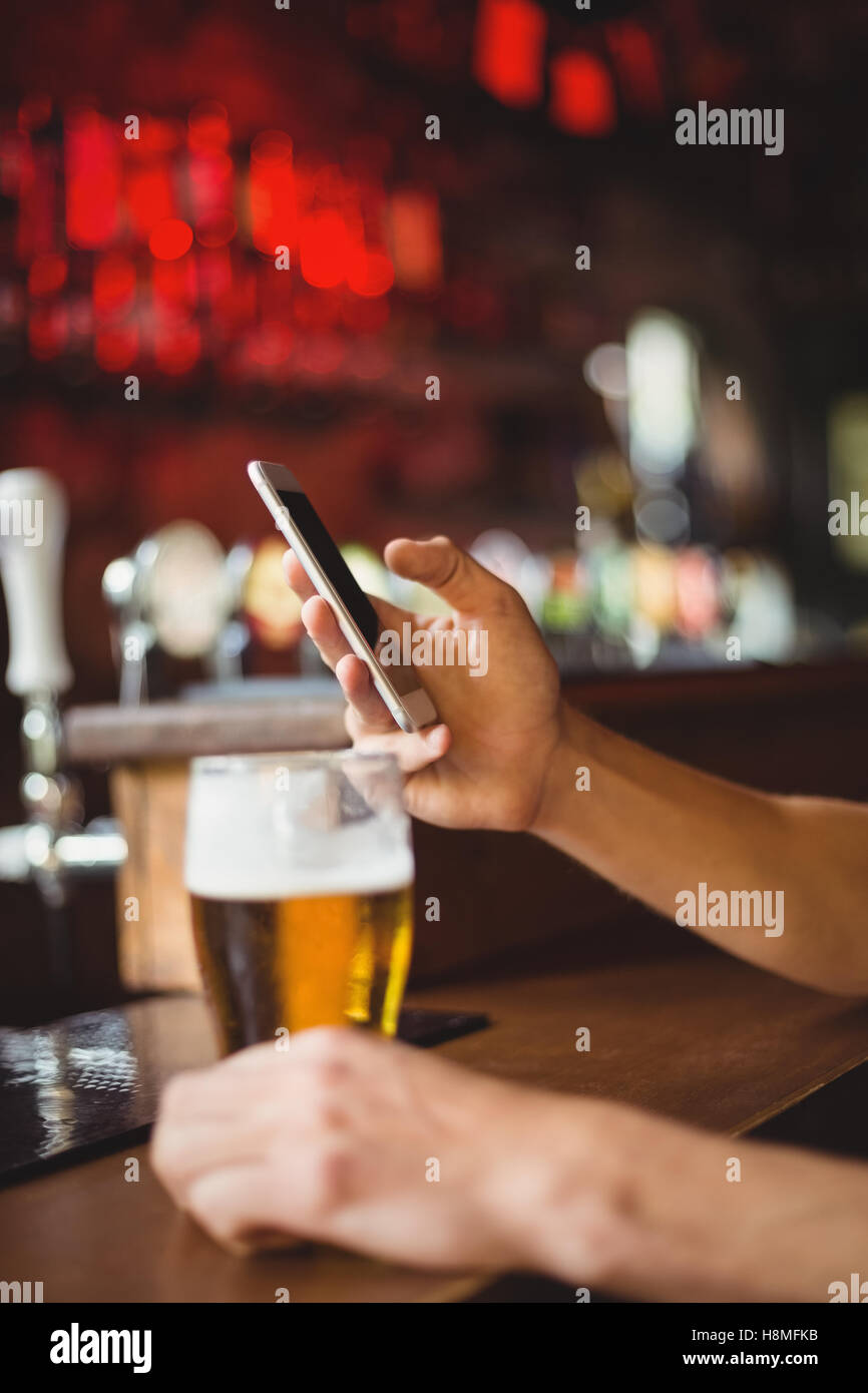 Man with glass of beer using mobile phone in counter Stock Photo - Alamy