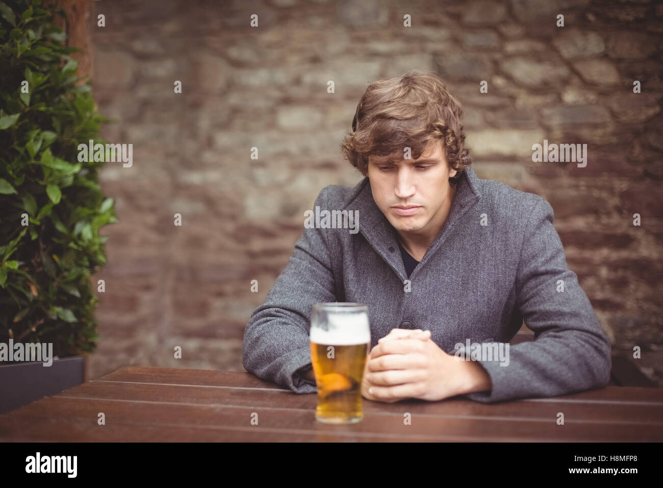 Man sitting in bar with glass of beer on table Stock Photo - Alamy