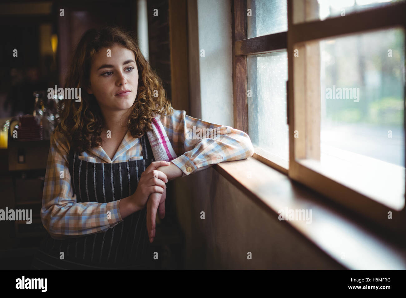Thoughtful waitress looking through window Stock Photo - Alamy
