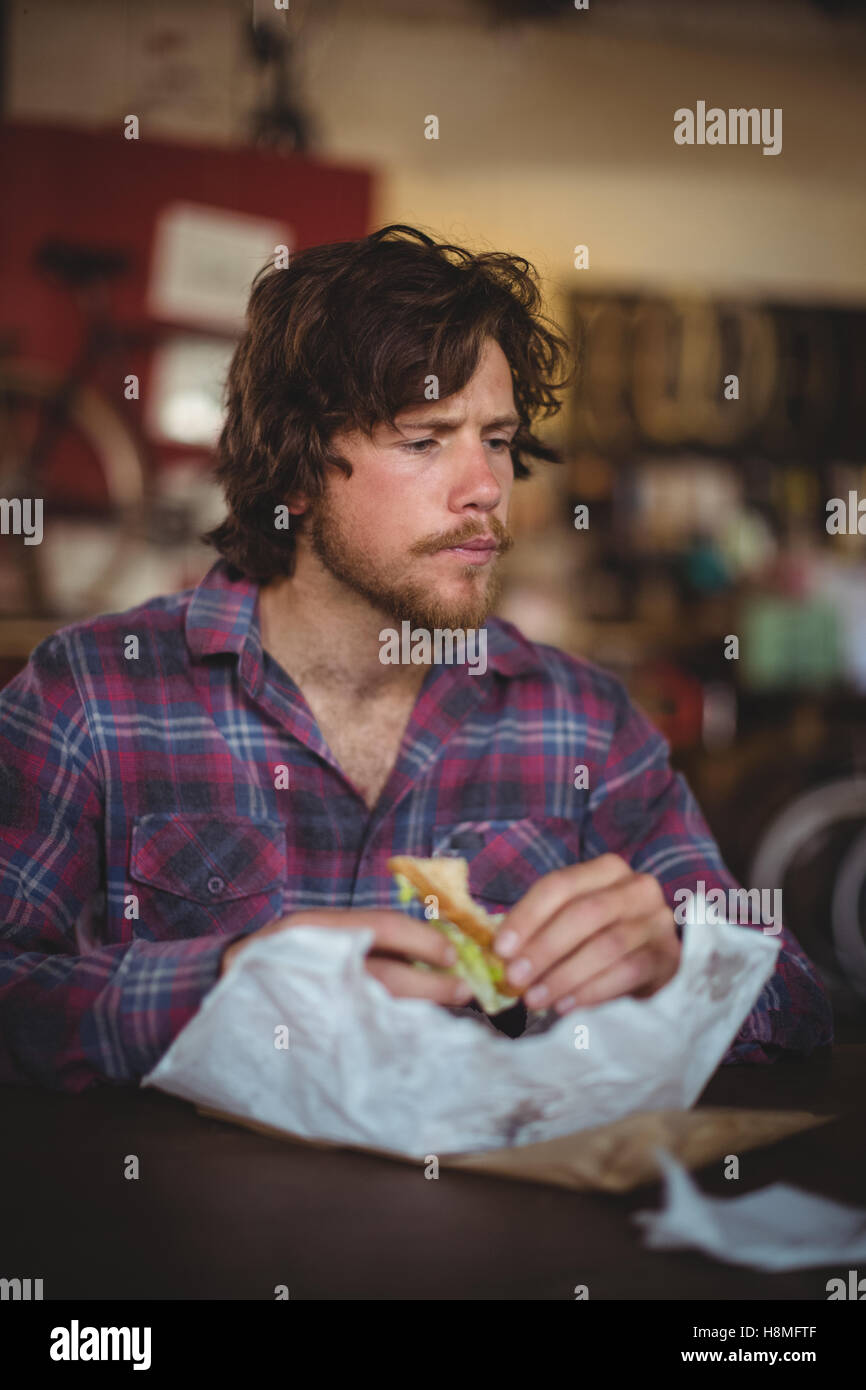 Man sitting at table and eating sandwich Stock Photo - Alamy