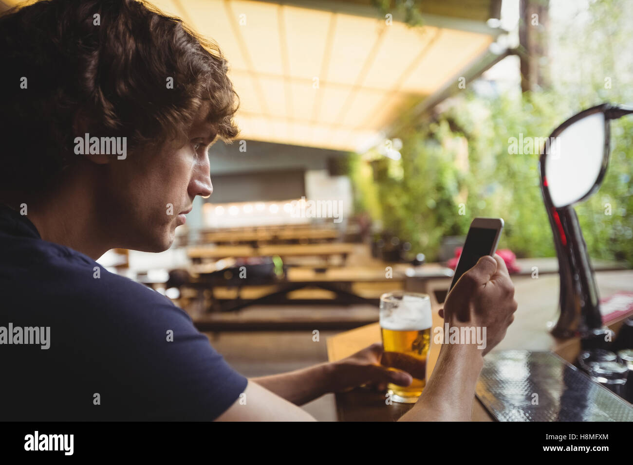 Man with glass of beer using mobile phone in counter Stock Photo - Alamy