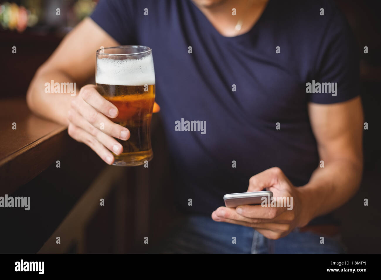 Man using mobile phone while having glass of beer Stock Photo - Alamy