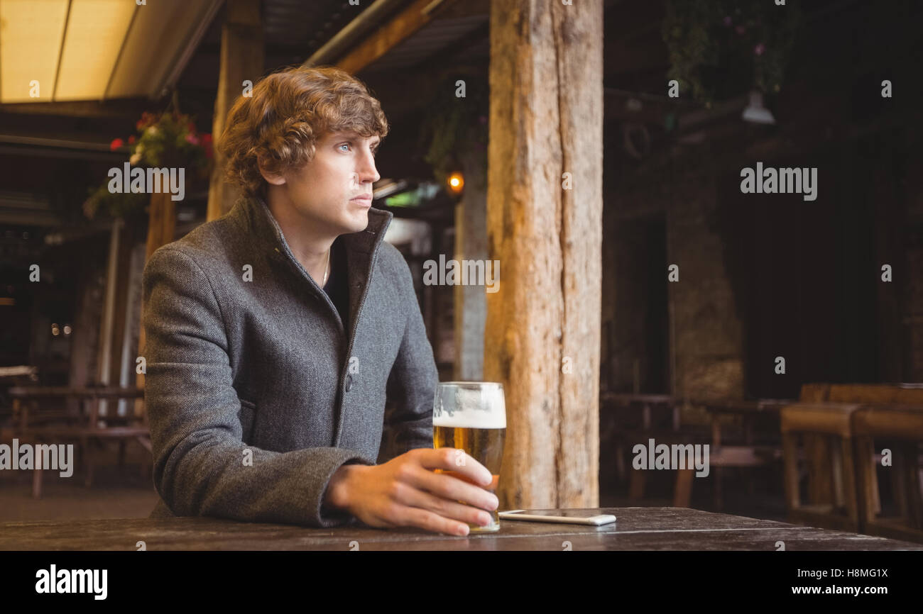 Man sitting in bar with glass of beer on table Stock Photo - Alamy