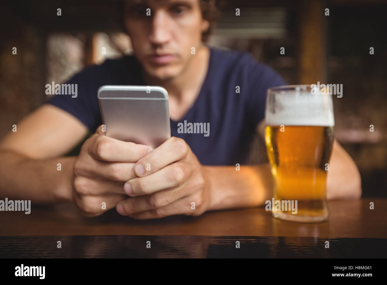 Man using mobile phone with beer glass on table Stock Photo - Alamy