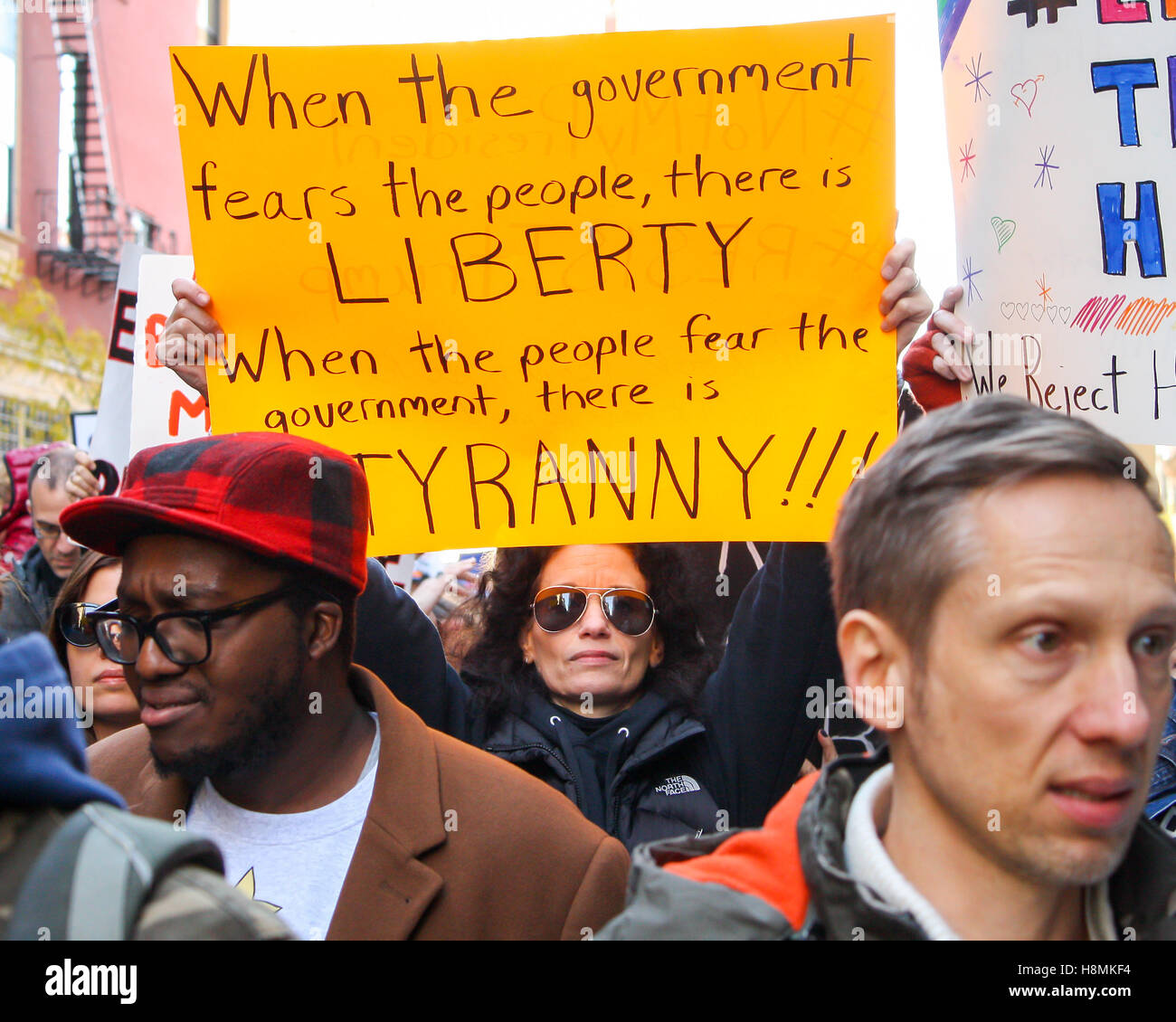 Woman carries large yellow sign to protest Donald Trump in New York, NY ...
