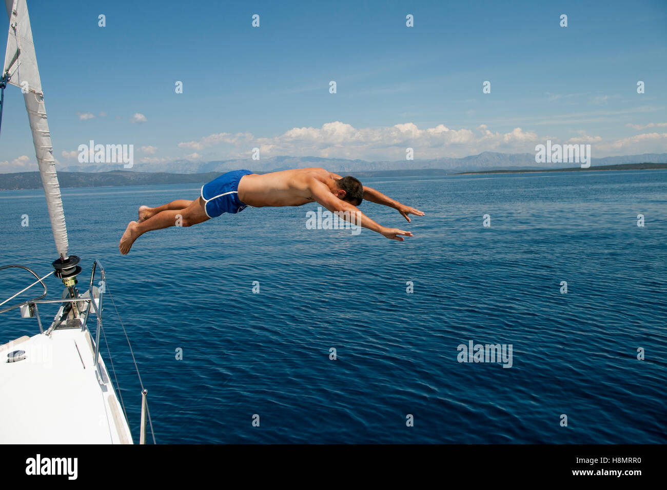 Man diving into sea from bow of sailboat Stock Photo - Alamy