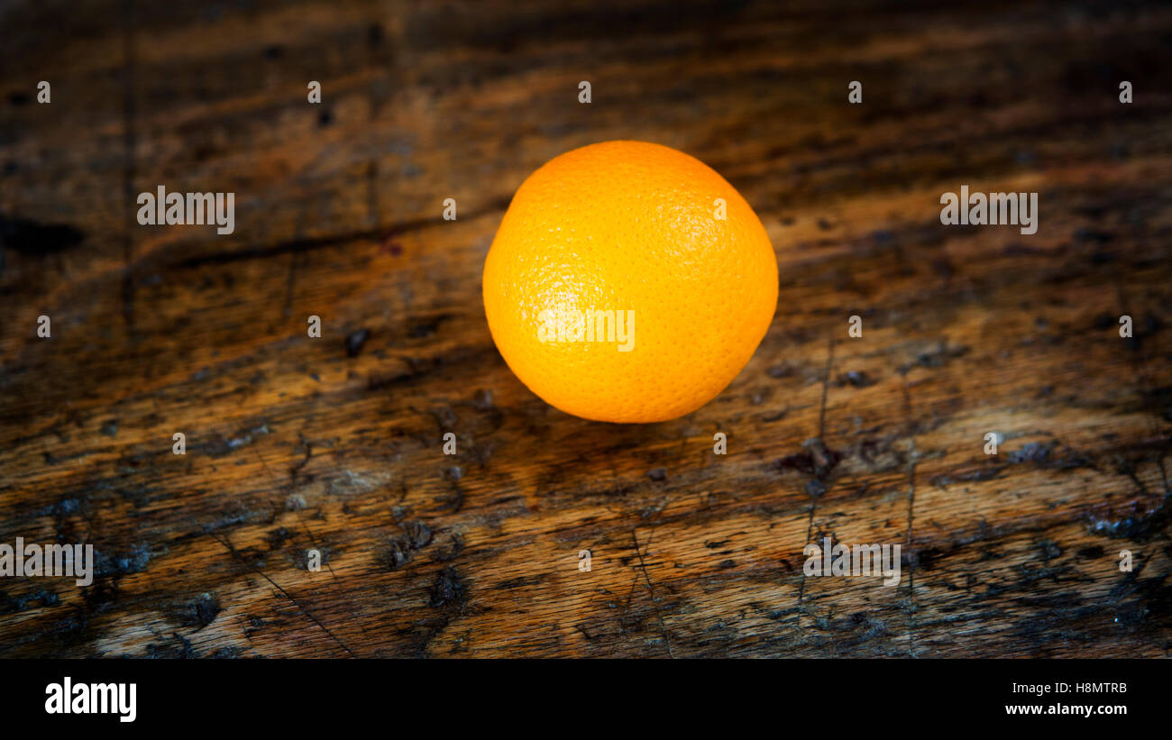 an orange on a rustic wooden table Stock Photo - Alamy